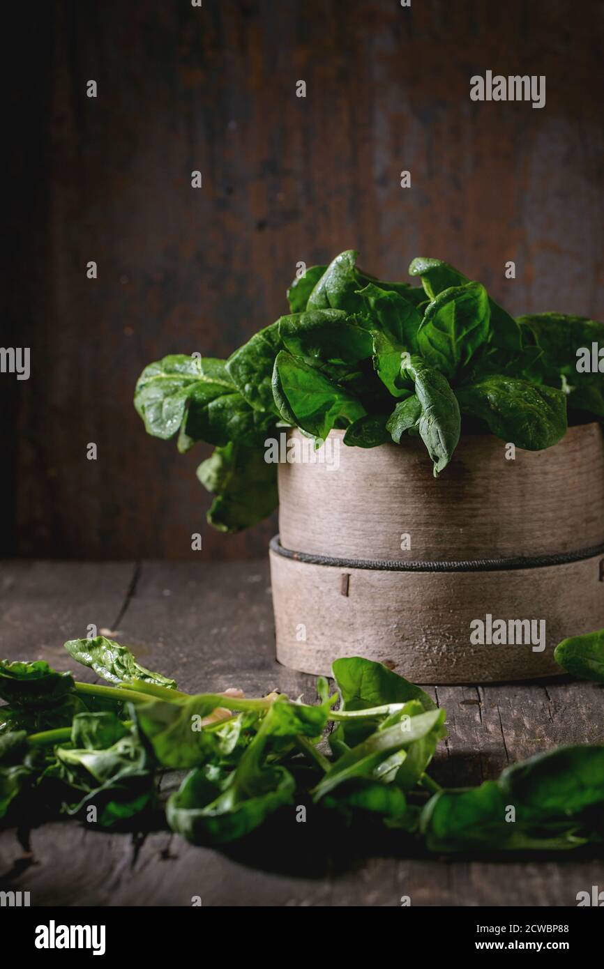 Bunch of fresh spinach with roots in vintage wooden sieve over old ...