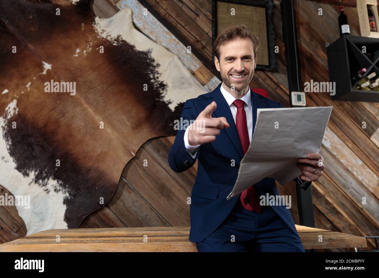 happy young businessman pointing finger, smiling and reading newspaper ...