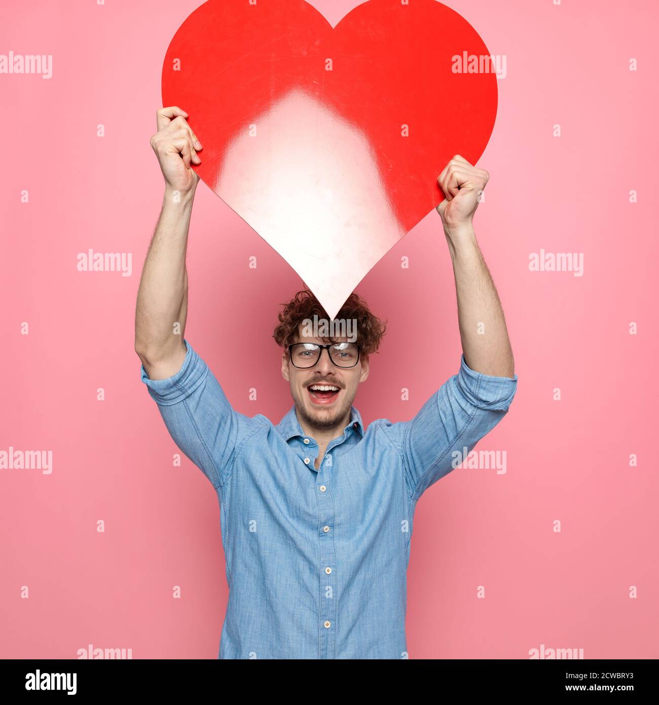 happy casual guy holding big red heart above head and smiling, standing ...