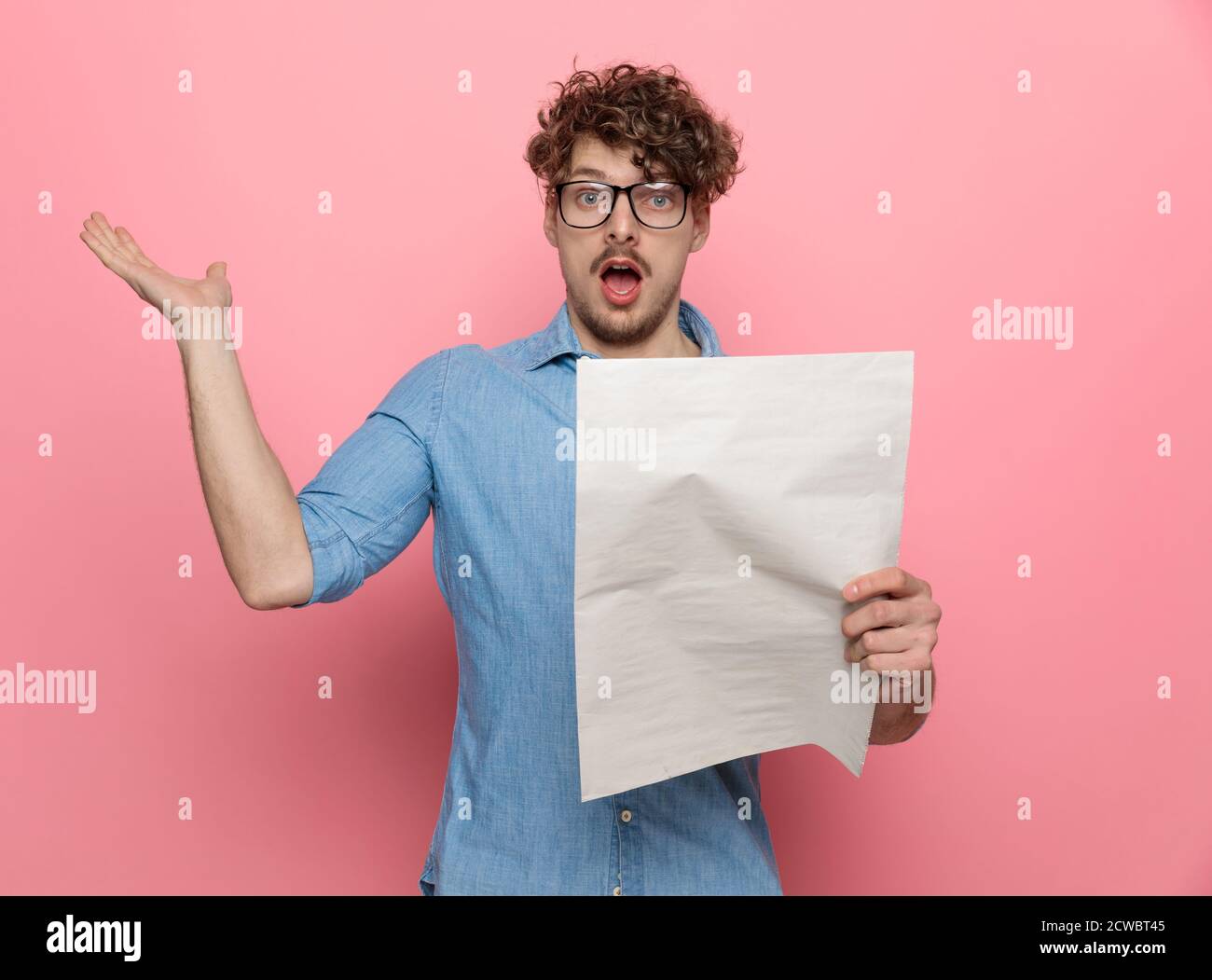 shocked young guy reading newspaper, holding hand to side and ...