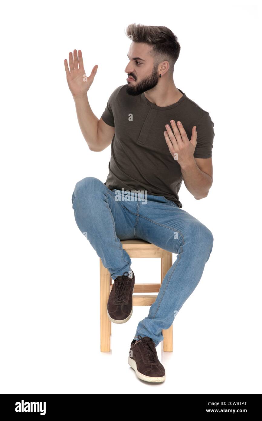 Angry casual man gesturing and arguing while sitting on a chair on ...