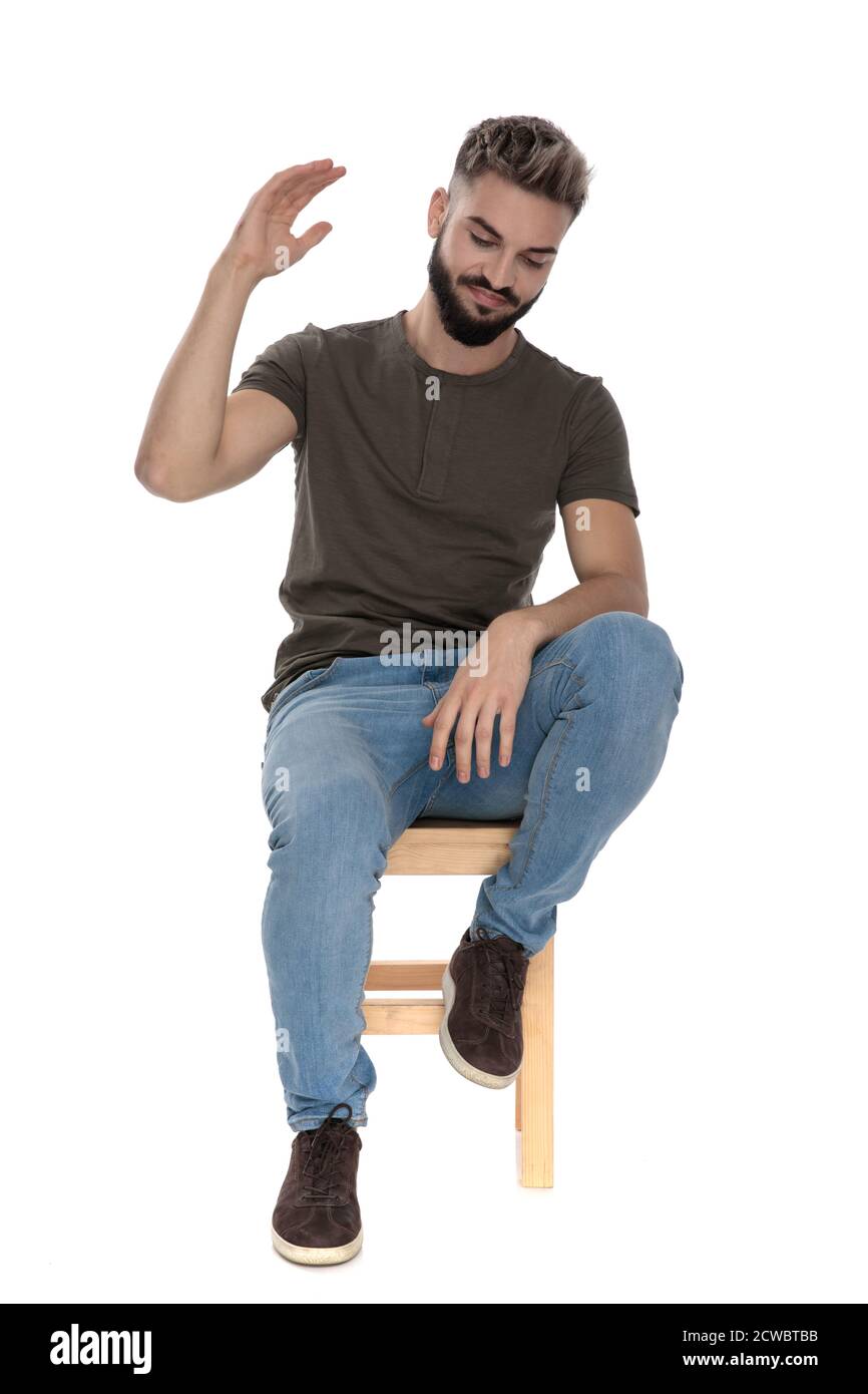 Upset casual man thinking and gesturing while sitting on a chair on ...