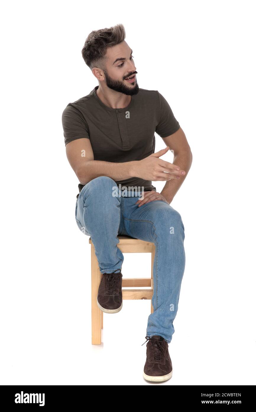 Positive casual man smiling and explaining while sitting on a chair on ...