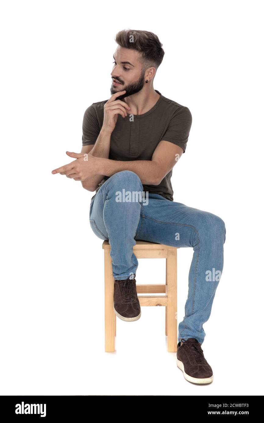 Young casual man smiling and reaching for a handshake while sitting on ...
