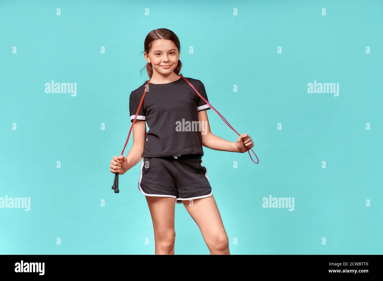 Cute teenage girl in black sportswear with jumping rope looking at ...