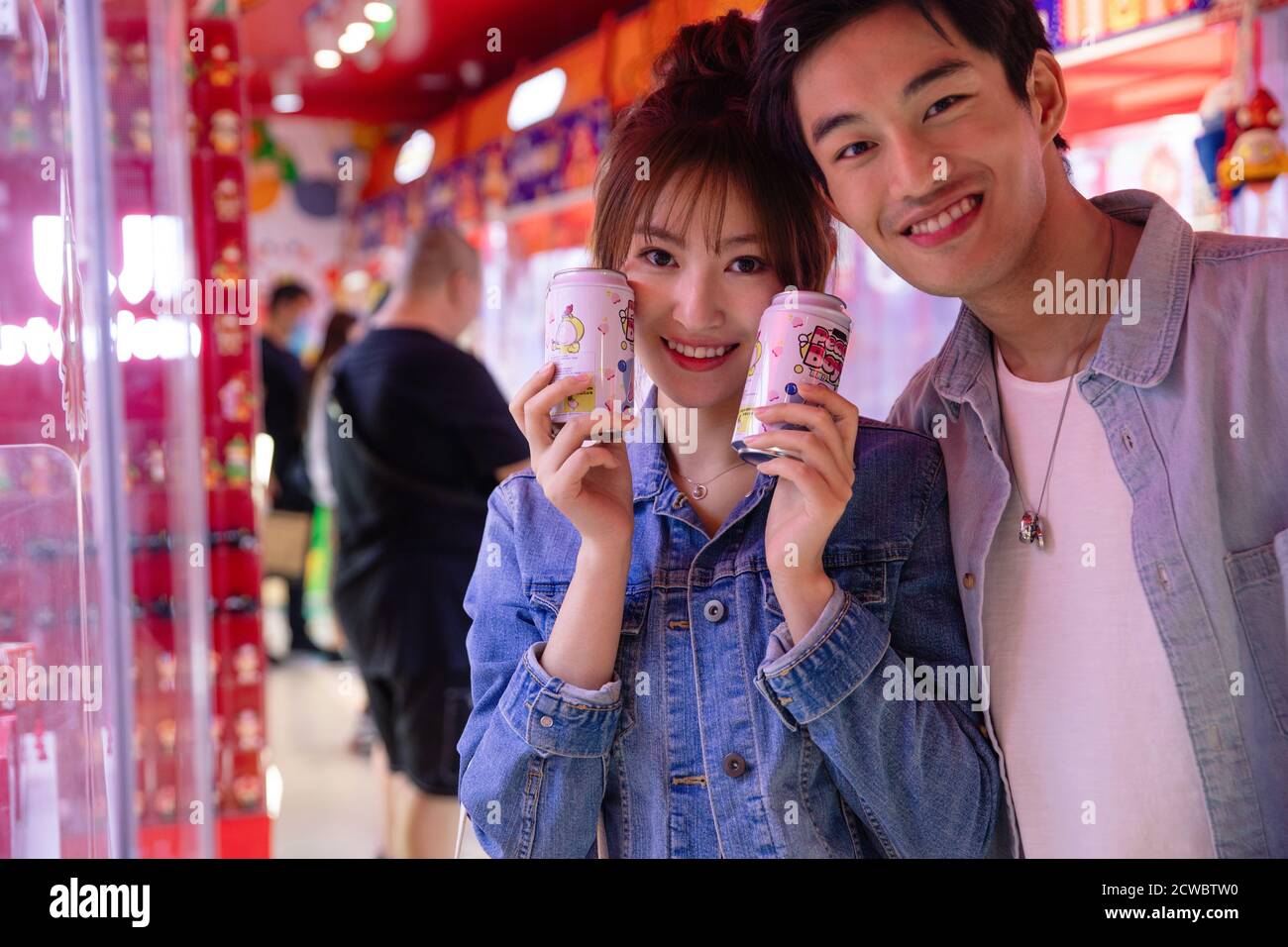 Standing beside the doll grabbing machine young couples Stock Photo - Alamy
