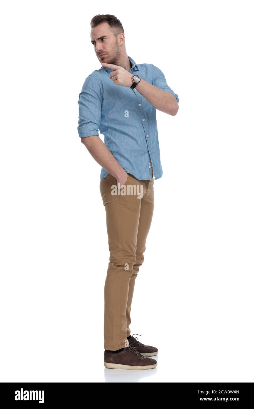Side view of upset casual man pointing and frowning while wearing blue ...