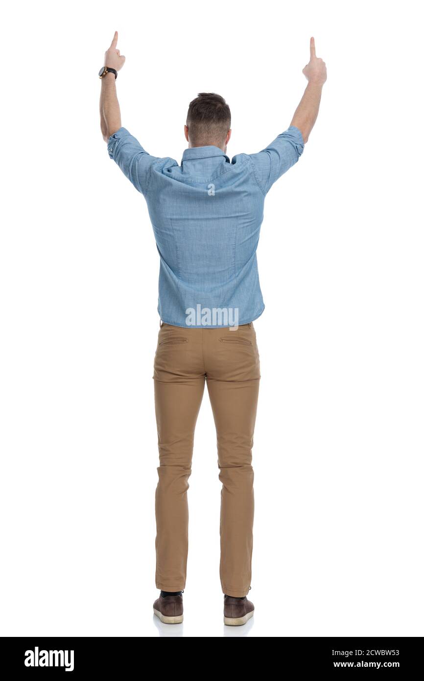 Rear view of casual man pointing up with both hands while wearing blue ...