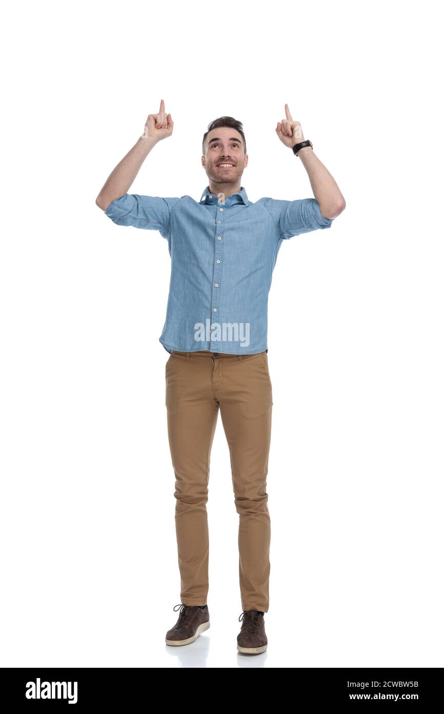 Happy casual man pointing up with both hands while wearing blue shirt ...