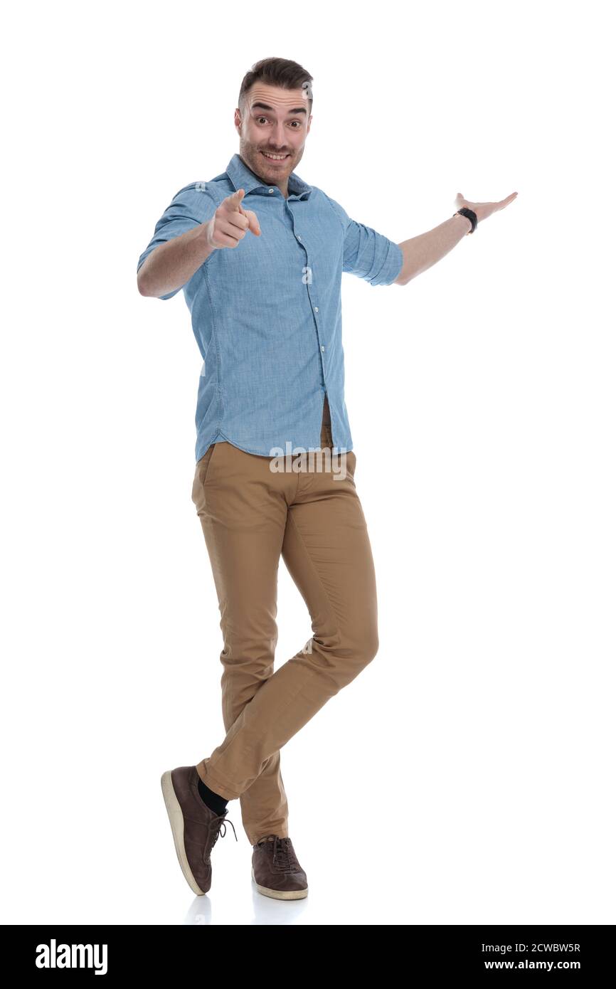 Cheerful casual man pointing and presenting while wearing blue shirt ...