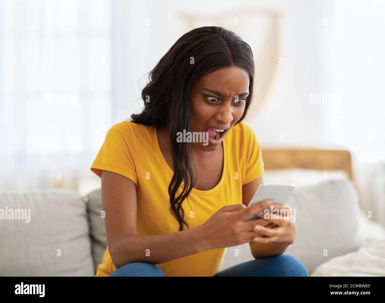 Young black lady receiving awful news, angry at her mobile phone at ...