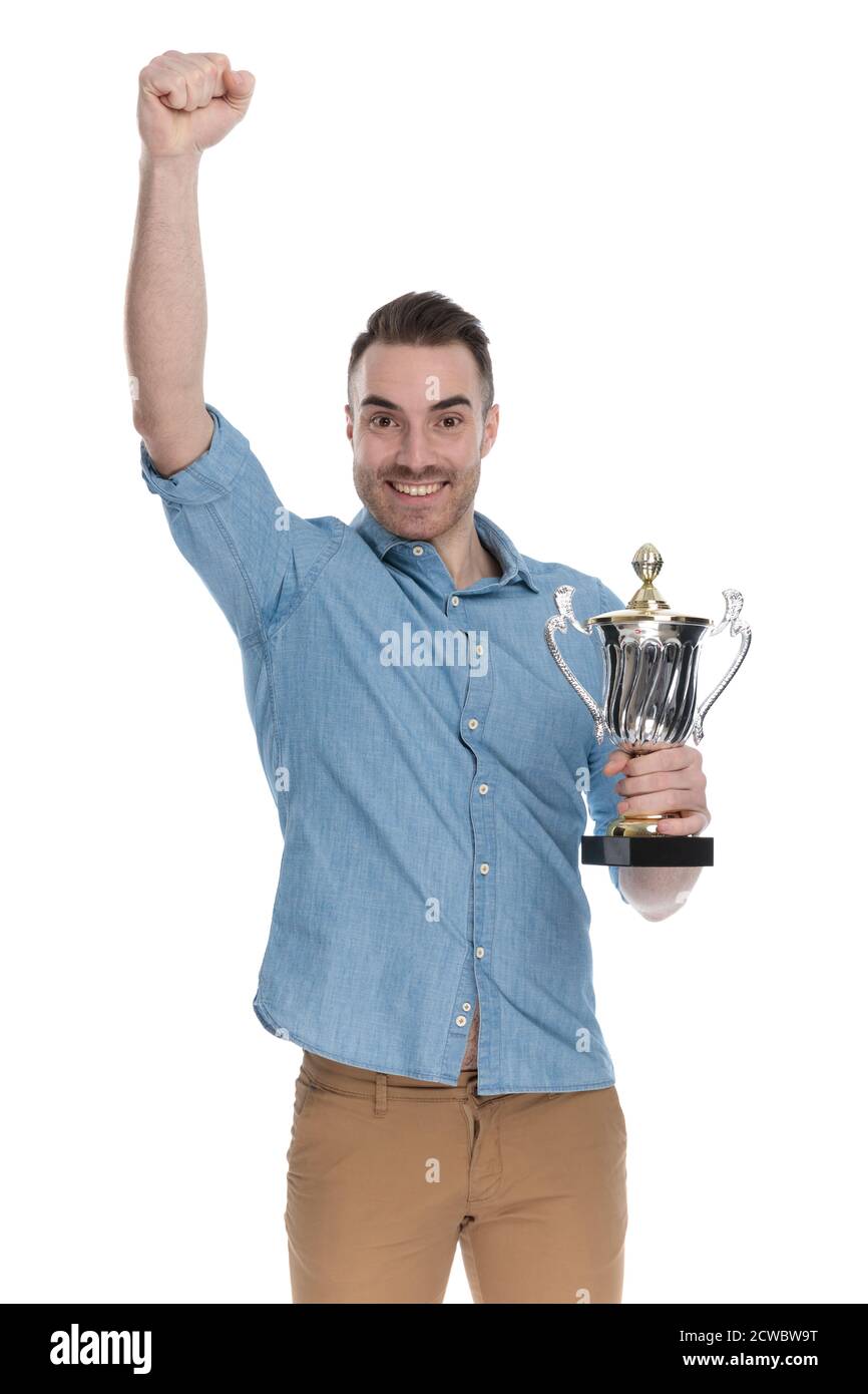 Cheerful casual man holding trophy and celebrating while wearing blue ...