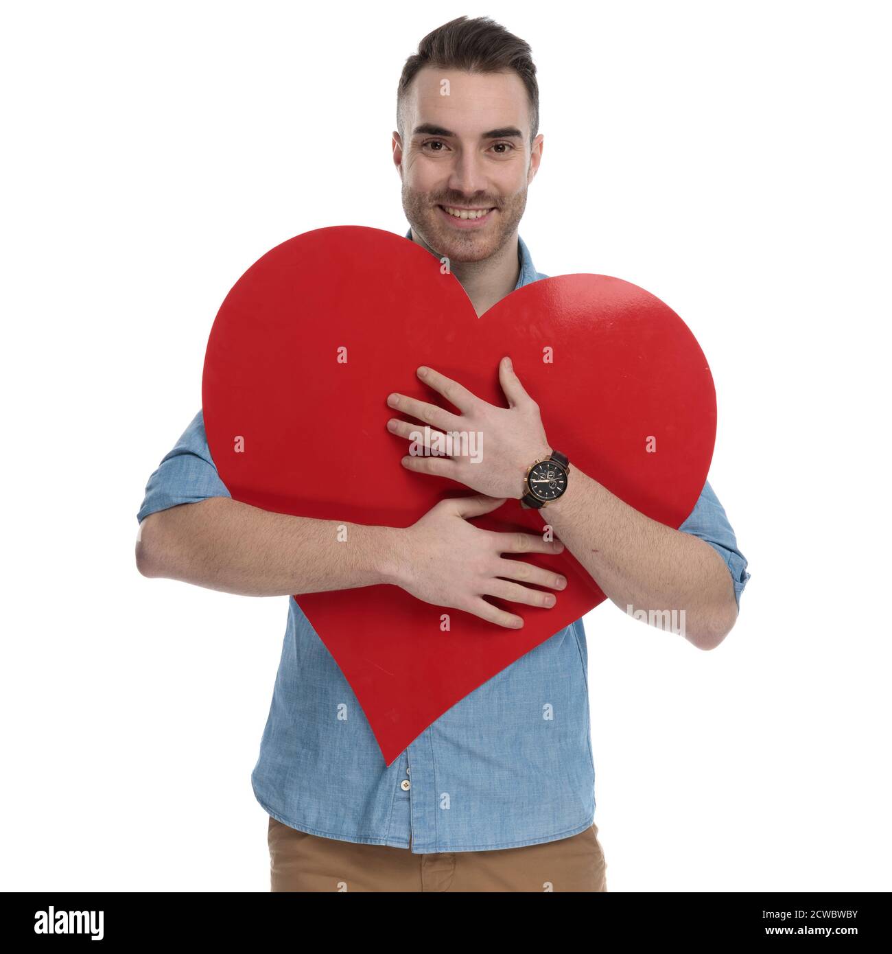 Happy casual man hugging heart shape and smiling while wearing blue ...