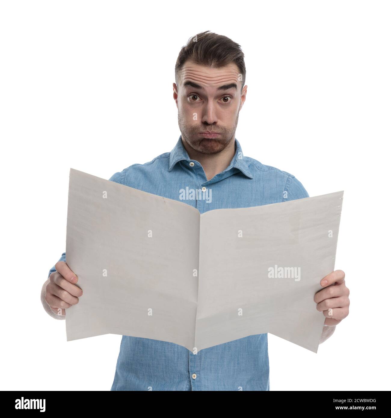 Disturbed casual man reading and newspaper and frowning while wearing ...