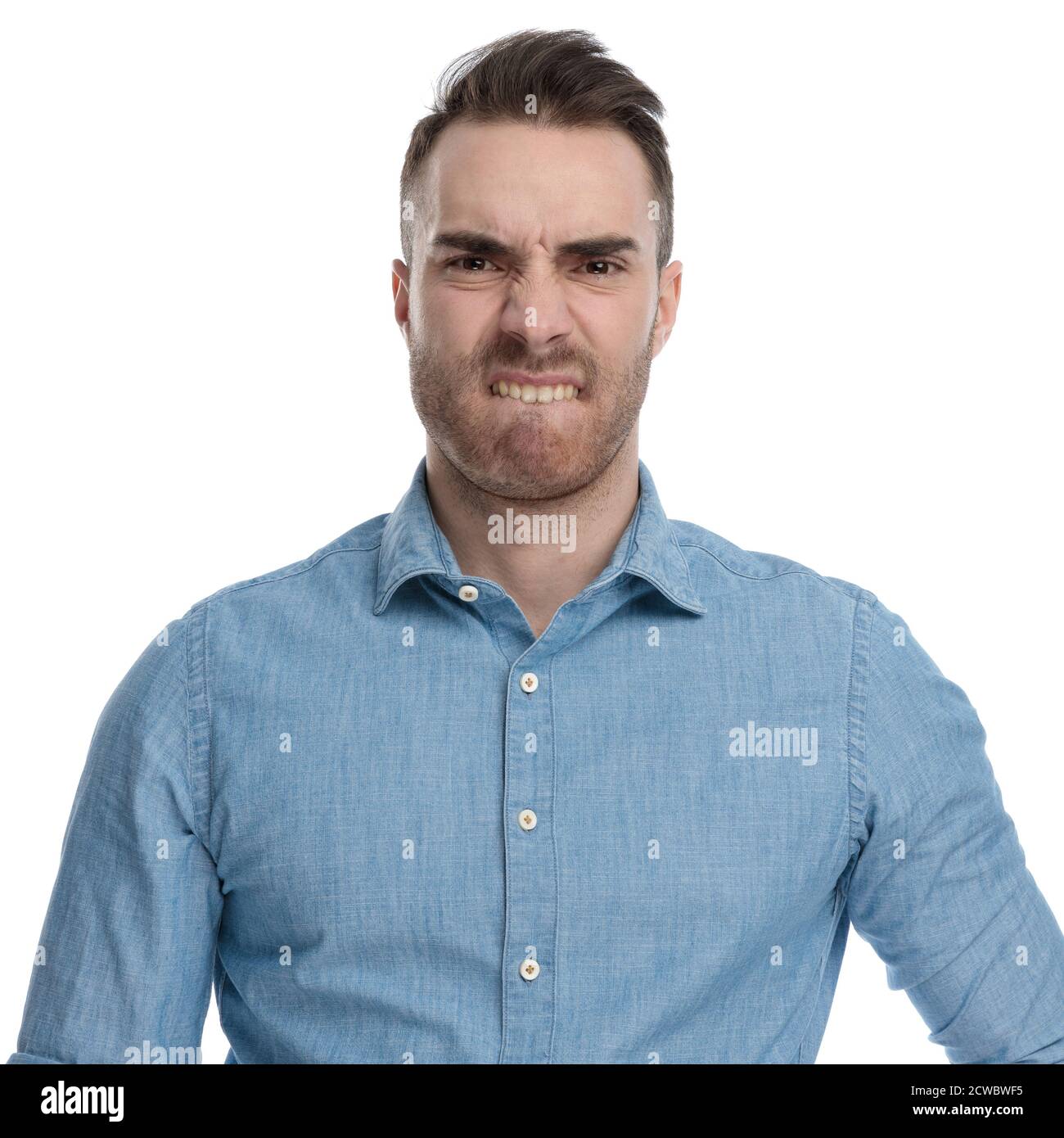 Bothered casual man biting his lips and frowning while wearing blue ...