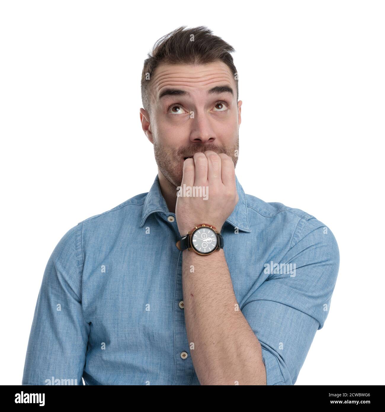Portrait of hopeful casual man looking up and chewing his nails while ...