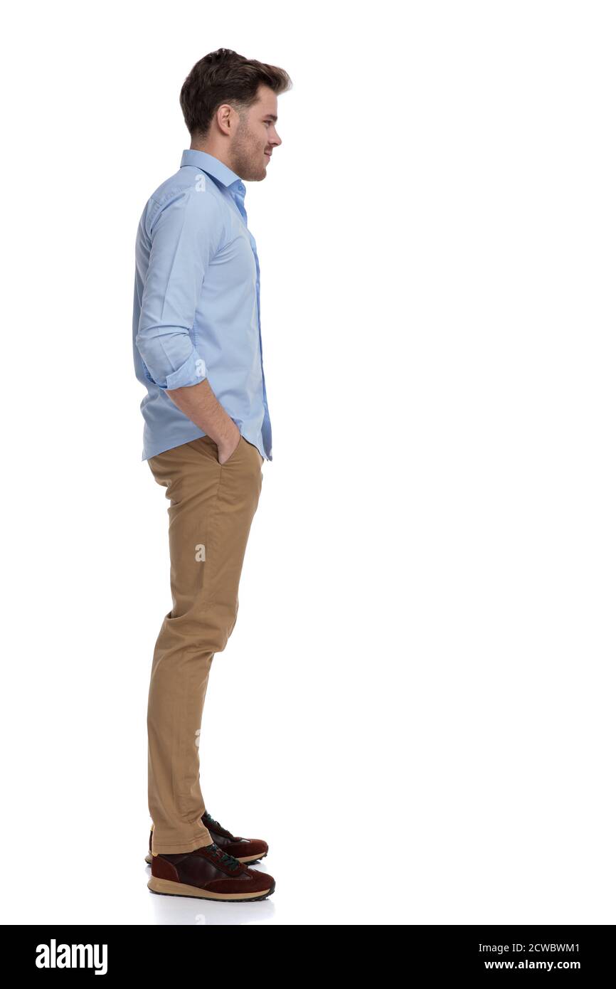 Side view of confident casual man holding both hands in pockets while ...