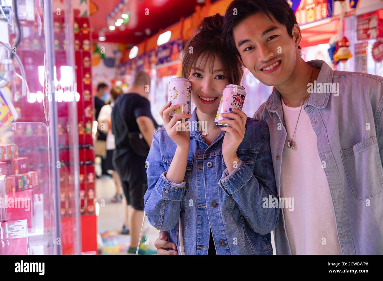 Standing beside the doll grabbing machine young couples Stock Photo - Alamy