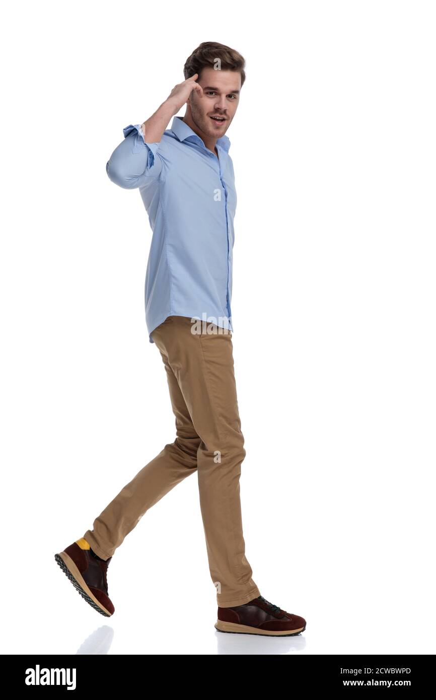 Side view of handsome casual man saluting while walking on white studio ...
