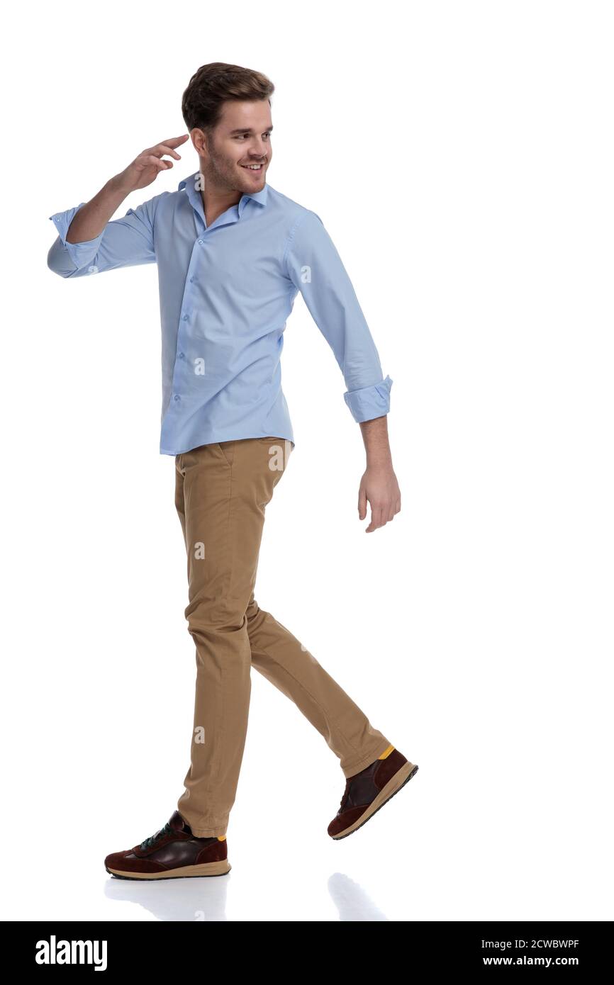 Side view of happy casual man smiling and greeting while walking on ...