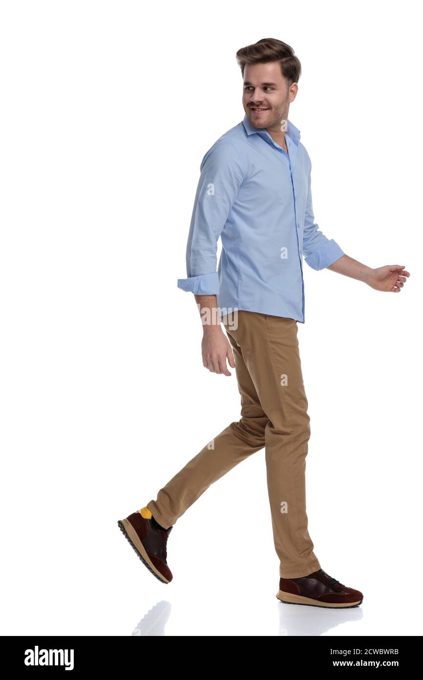 Side view of happy casual man looking over shoulder while walking on ...