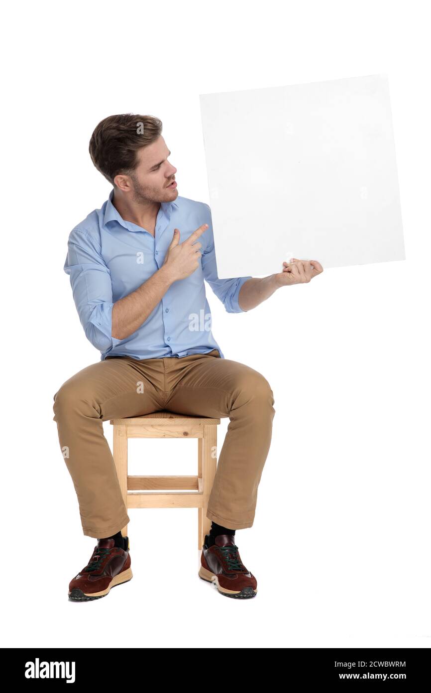 Confused casual man looking at the wallpaper he is holding while ...