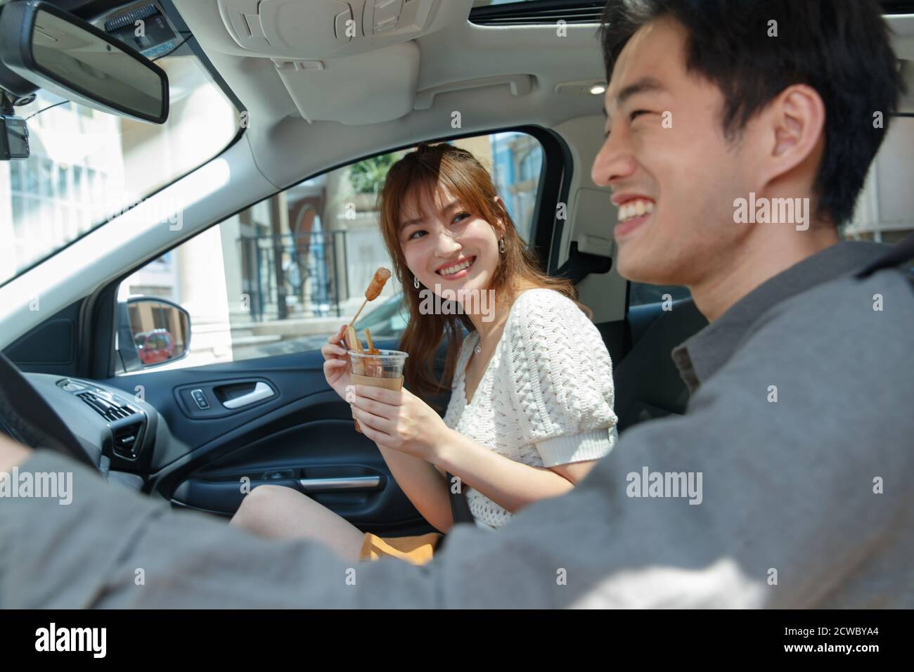 The young couple to eat in the car Stock Photo - Alamy