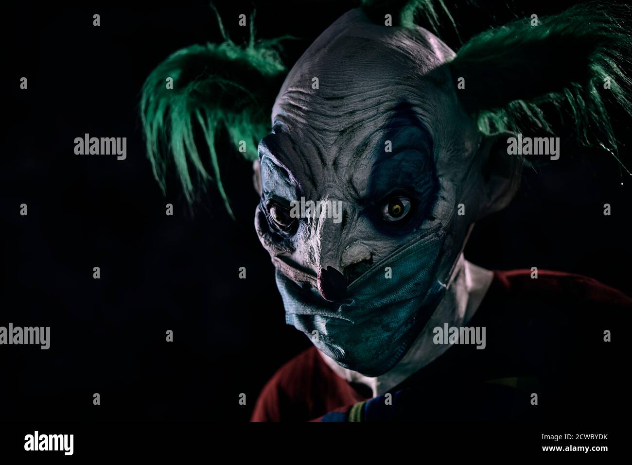 closeup of a disturbing evil clown, with green hair, wearing a dirty ...