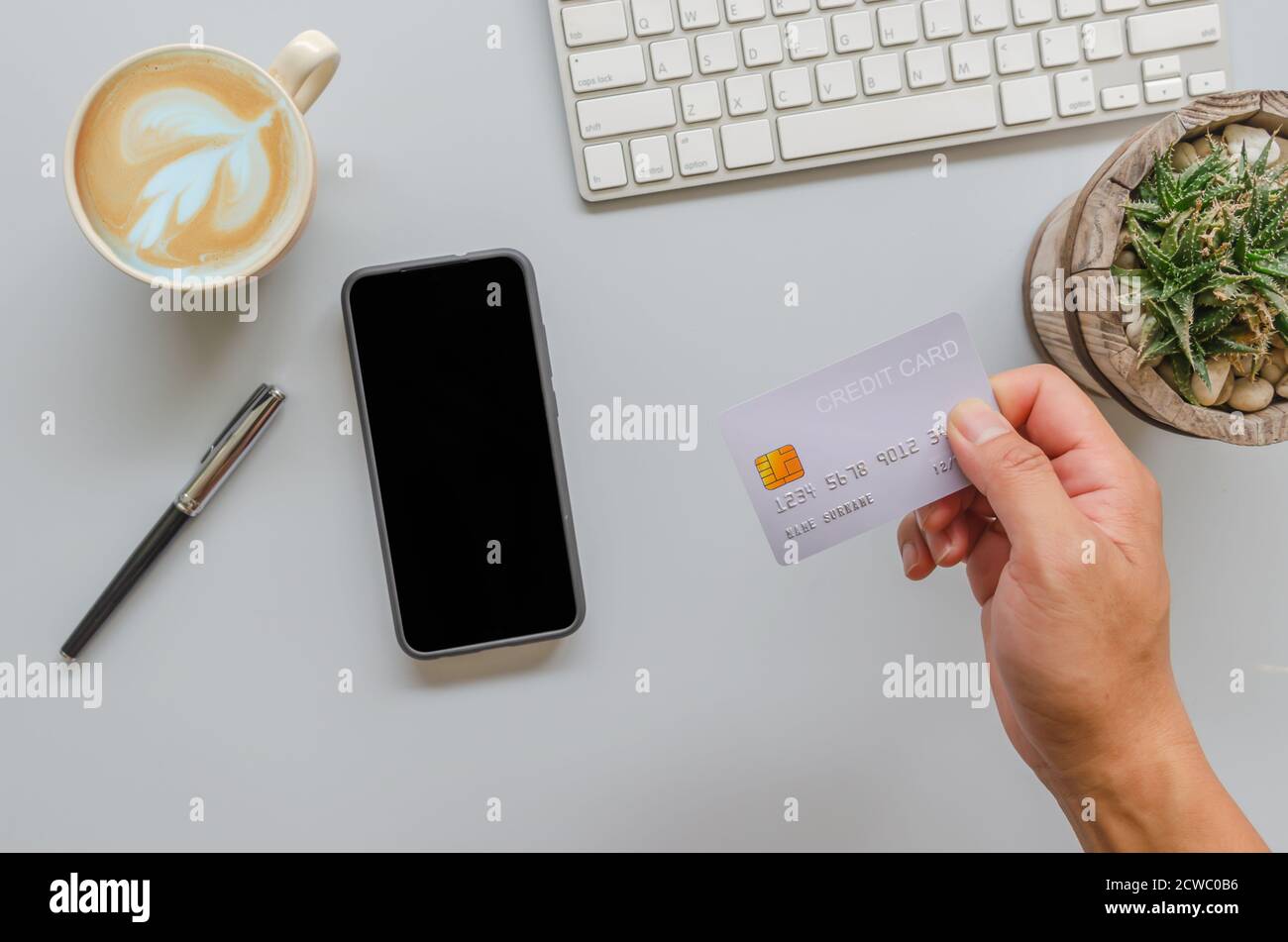 Top view man holding a credit card on the desk. computer ,coffee,pen ...
