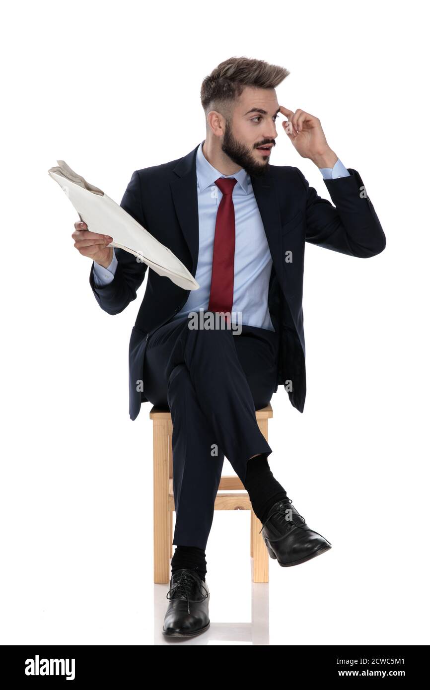 young businessman holding newspaper and pointing finger to head ...