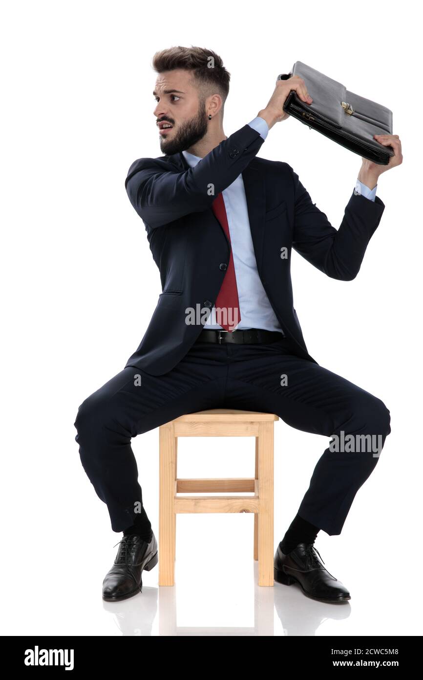 upset young businessman looking to side and throwing a suitcase ...