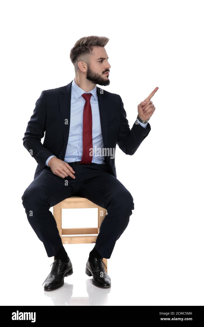 angry young businessman pointing finger to side and blaming, sitting ...