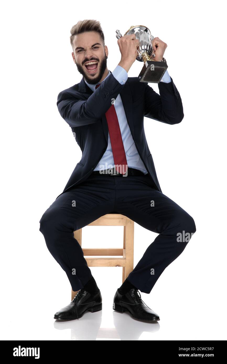 excited young businessman screaming and presenting trophy, sitting ...
