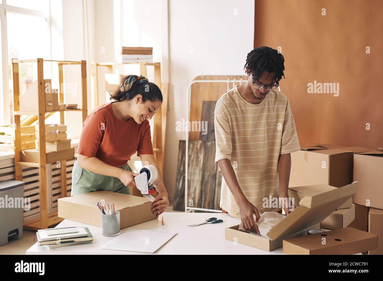 Two colleagues packing new clothes into the cardboard boxes at the ...