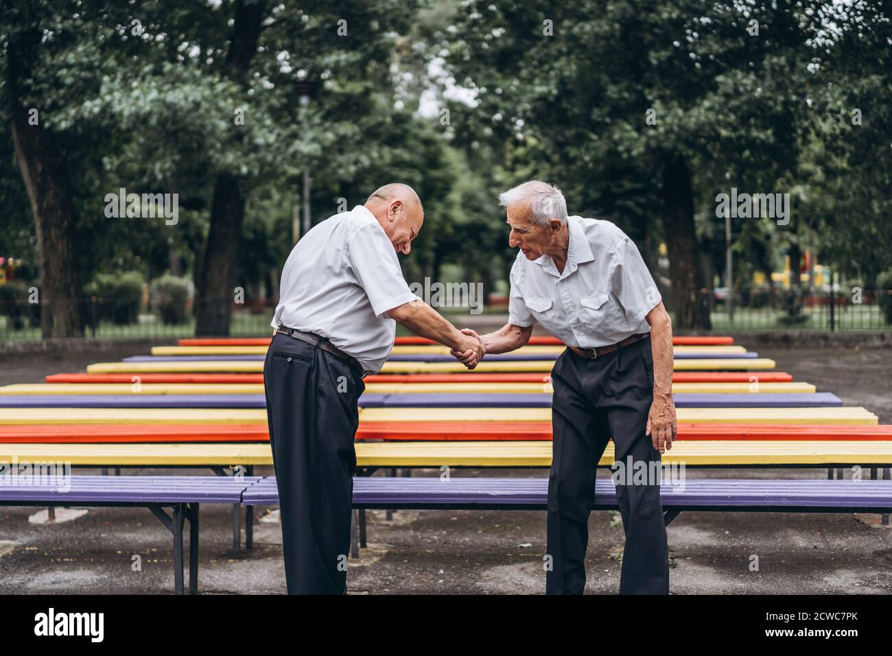 Two old senior adult men have a conversation outdoors in the city park ...