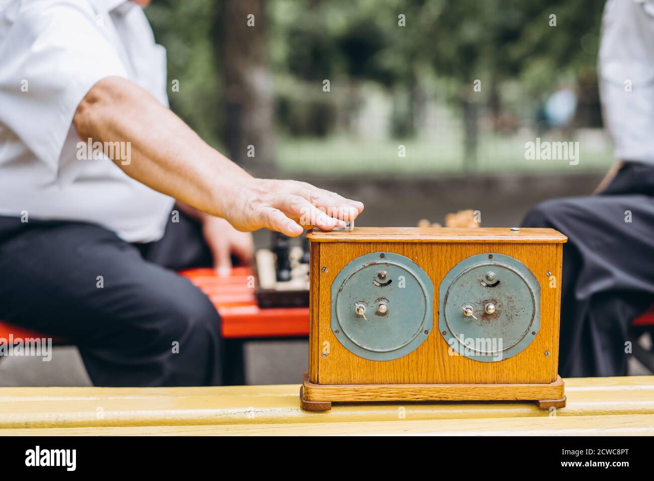Two senior adult men playing chess on the bench outdoors in the park ...