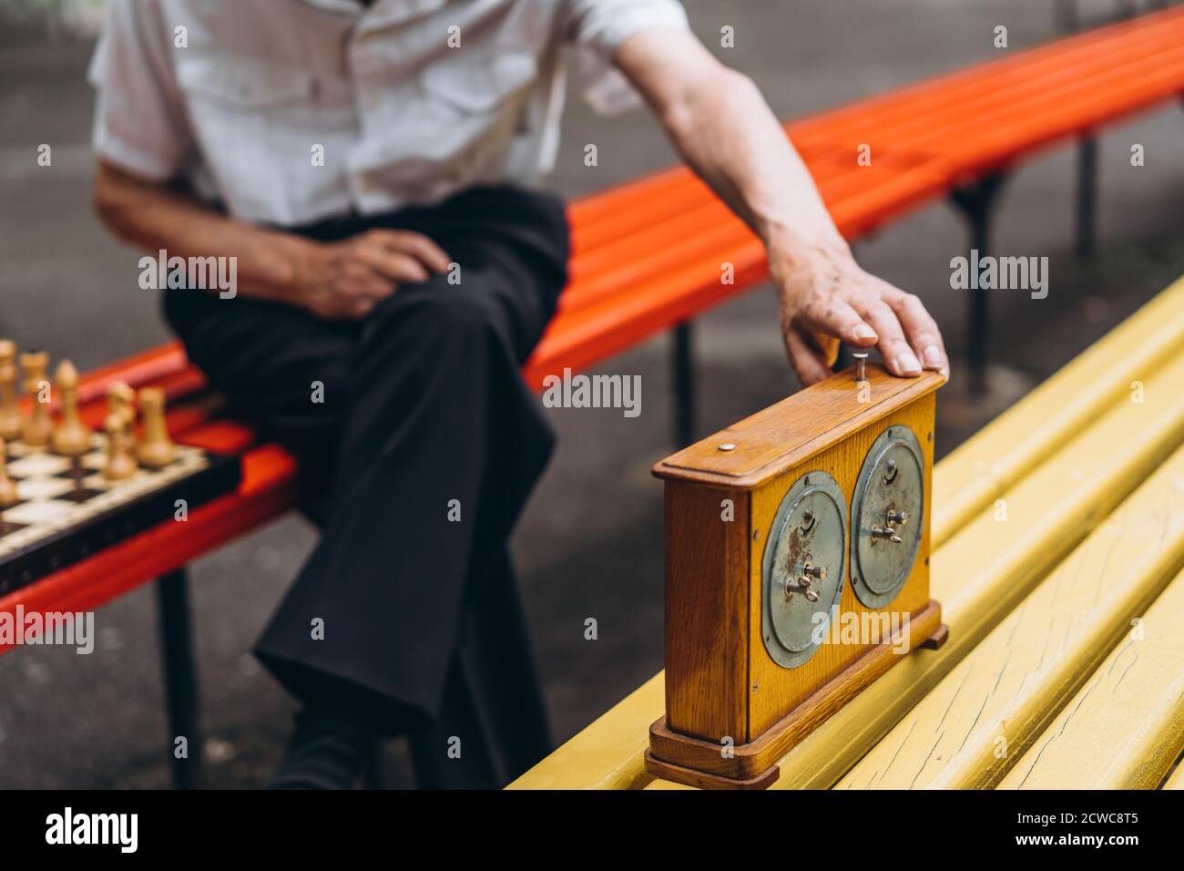 Two senior adult men playing chess on the bench outdoors in the park ...