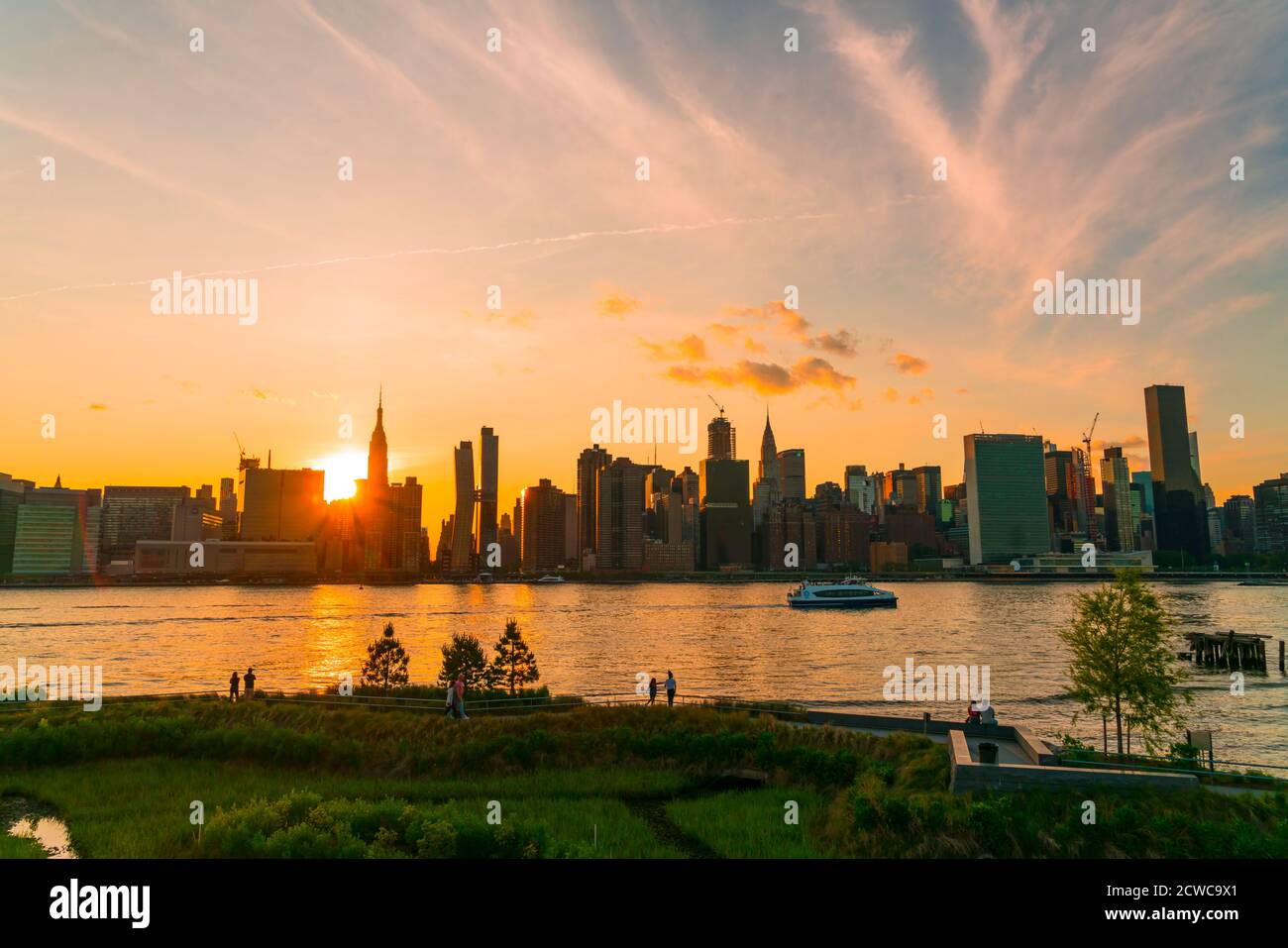 The sun sets to Manhattan skyscraper beyond the East River Stock Photo ...