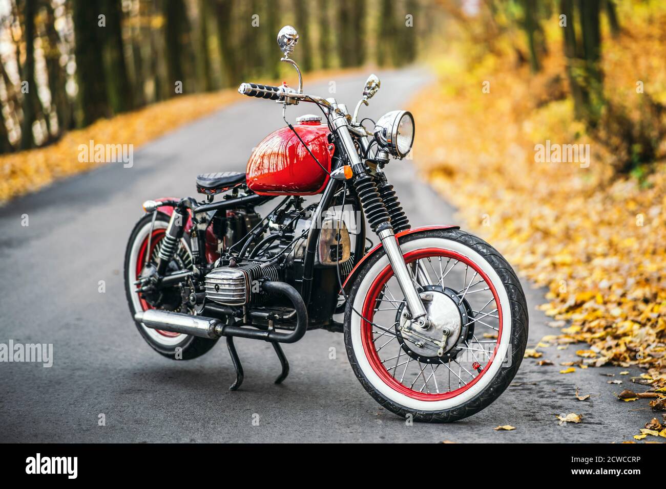 Red custom old fashioned motorcycle on the road in the forest with ...