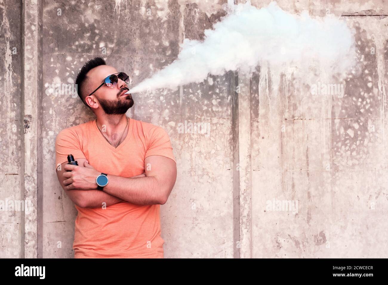 Vaper smoke electronic cigarette outdoor near wall Stock Photo - Alamy