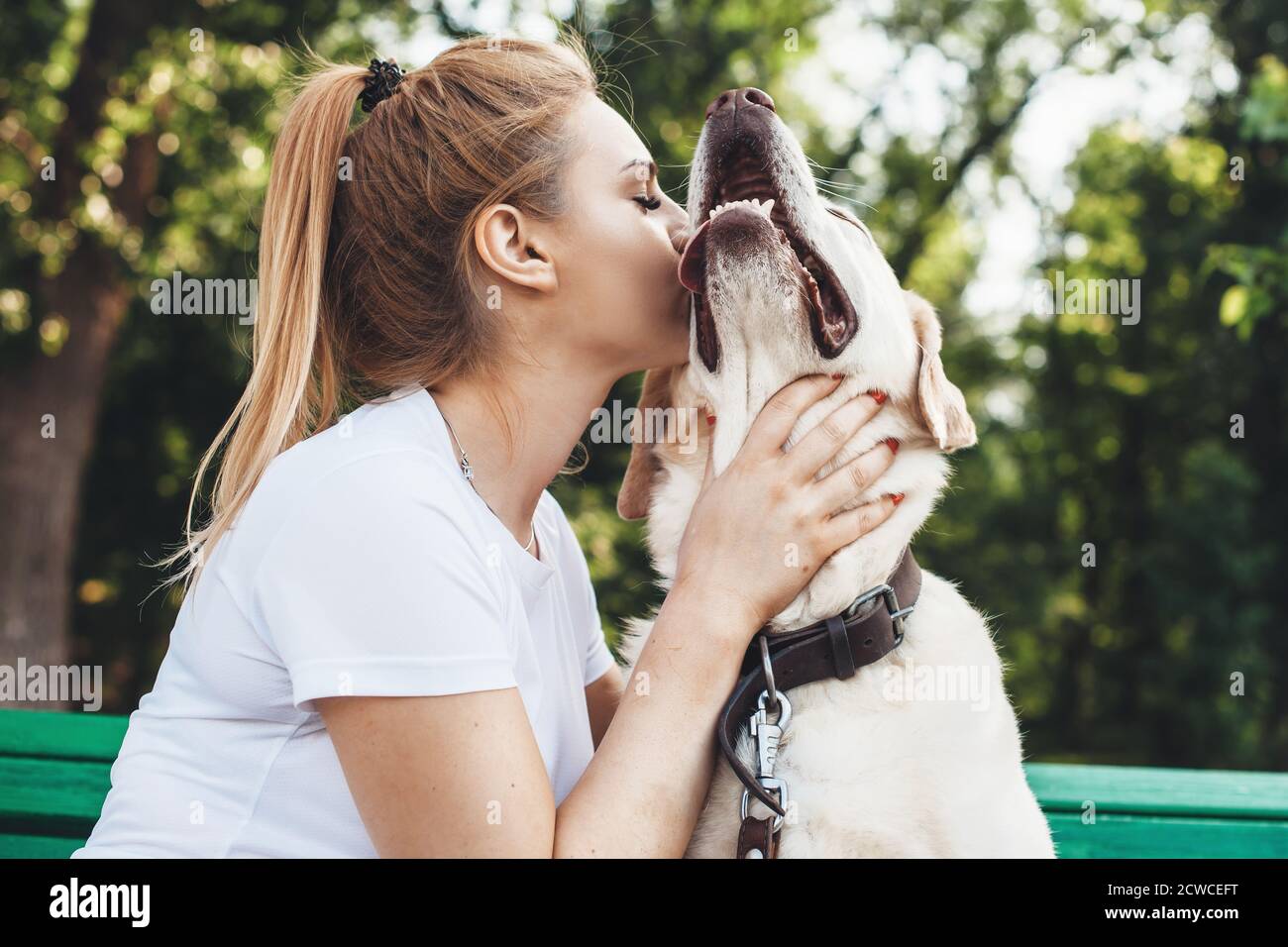 Close up photo of a caucasian woman kissing her labrador during a ...