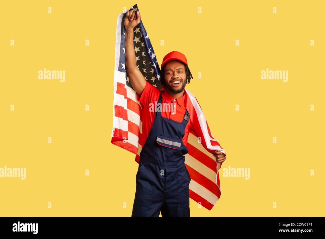 Happy afro-american handyman in uniform wrapped in usa flag shouting ...