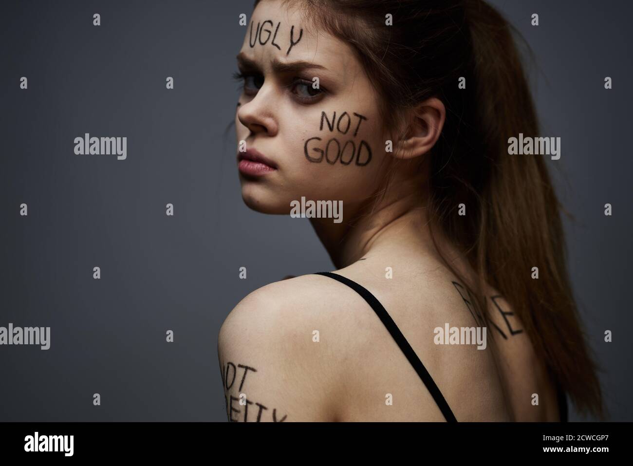 Emotional woman with inscriptions on body upset with frustration gray ...