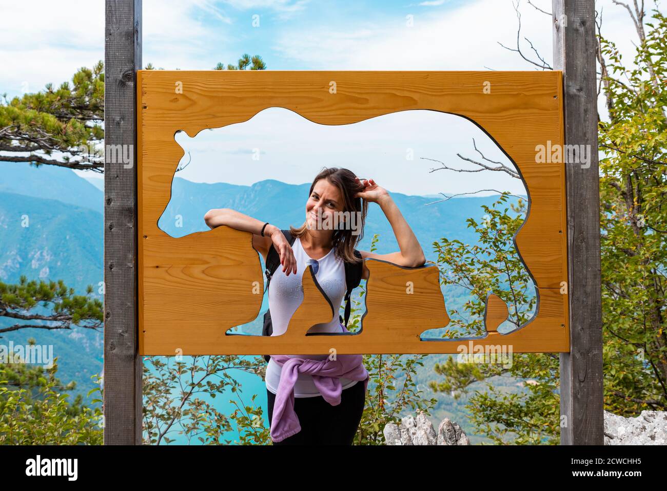 Woman hiker at mountain forest posing beside bear sign at natural ...