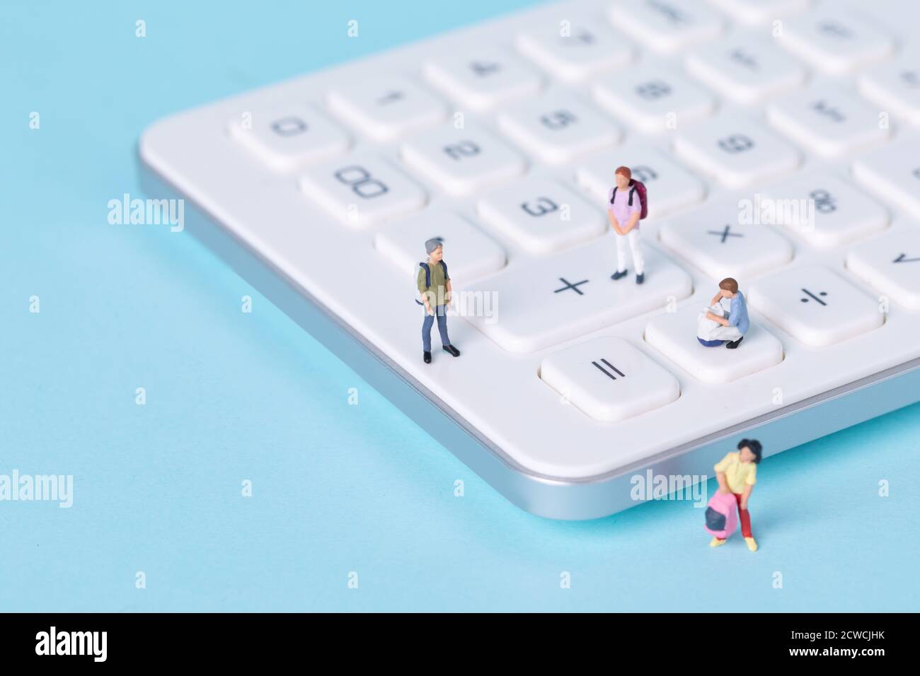 Closeup of a calculator with miniature figurines of students around it ...