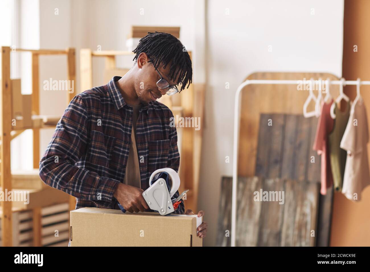 African young man working with parcels he packing box with adhesive ...