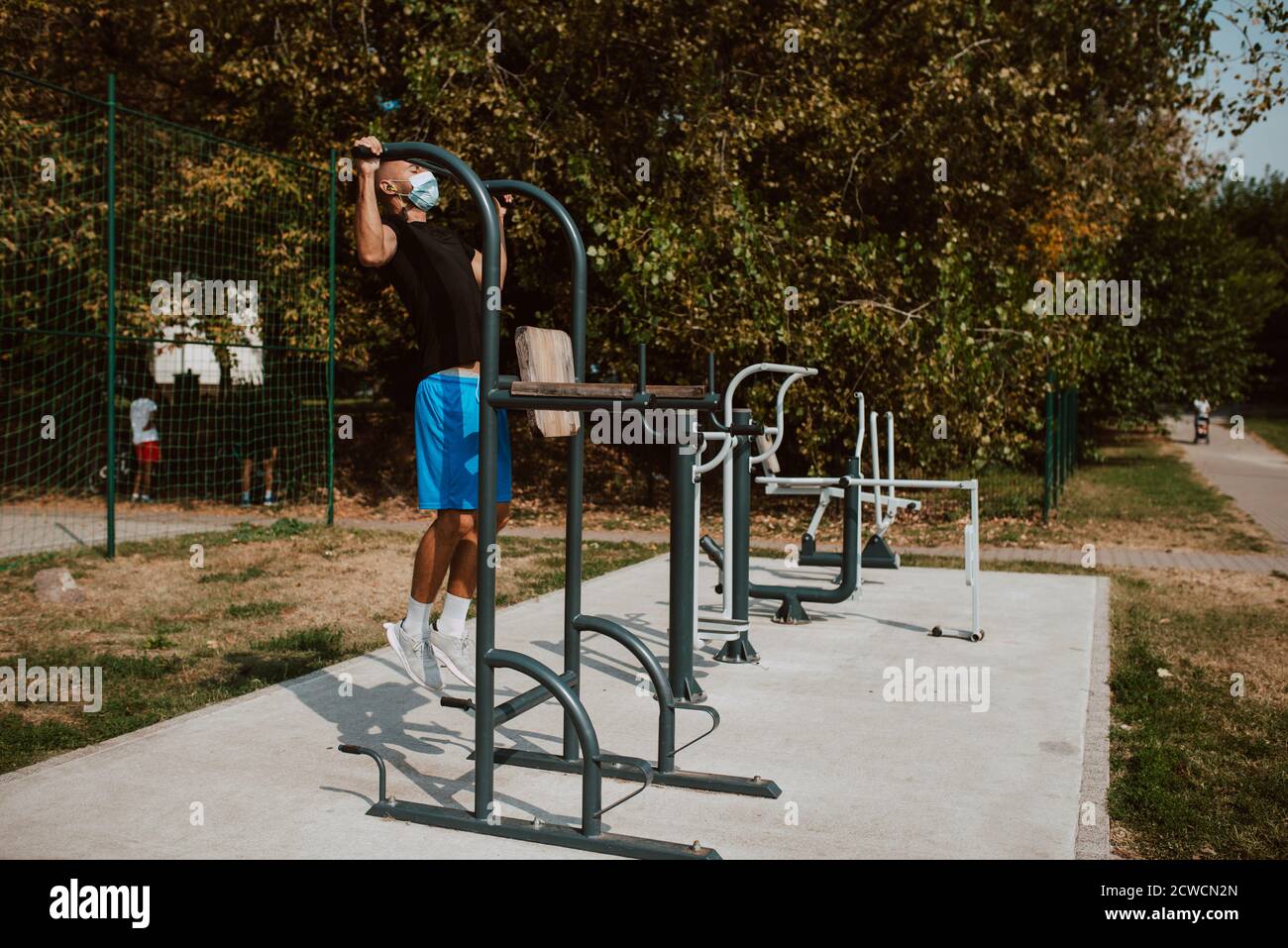 Fit young male caucasian athlete with face mask trains on arm and leg ...