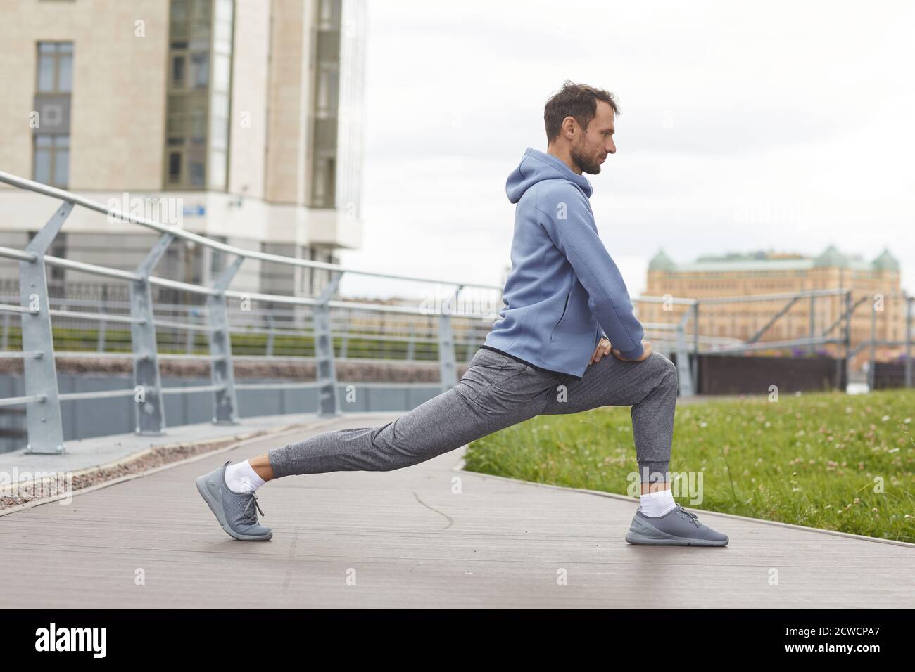 Young athlete doing stretching exercises outdoors he warming up before ...