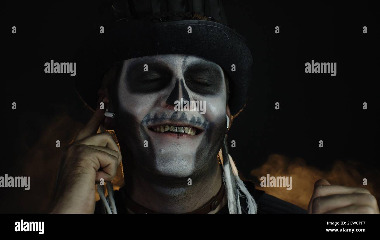 Sinister man with horrible Halloween skeleton makeup with top-hat puts ...