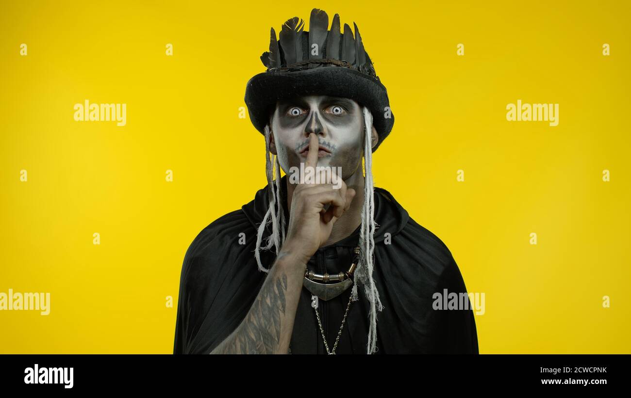 Creepy man with skeleton makeup in top-hat with feathers. Strict guy ...